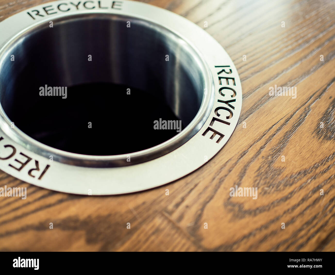 Close-up modern round recycle trash bin hole on wooden background in ...