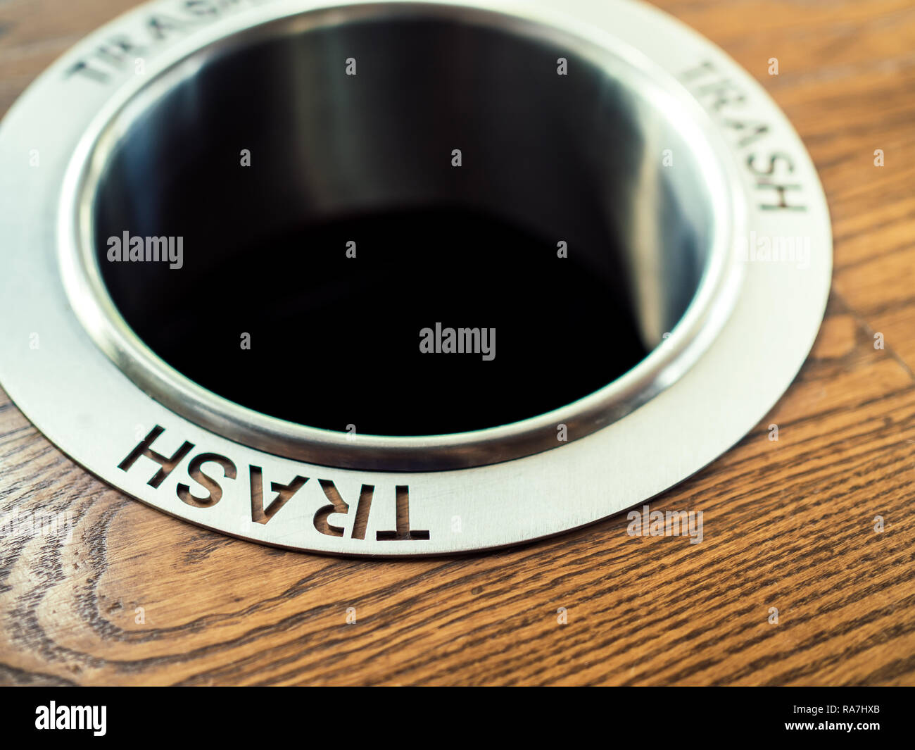 Close-up modern round trash bin hole on wooden background in coffee ...
