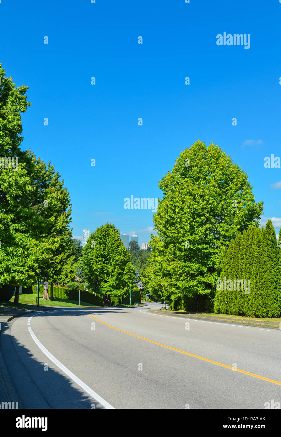 Suburban road curve leading to a city Stock Photo - Alamy