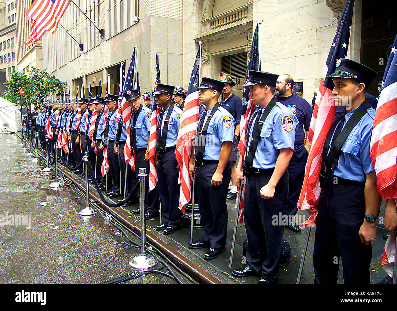 2003 - New York City Fire Department (NYCFD) Firefighters line a street holding American flags ...