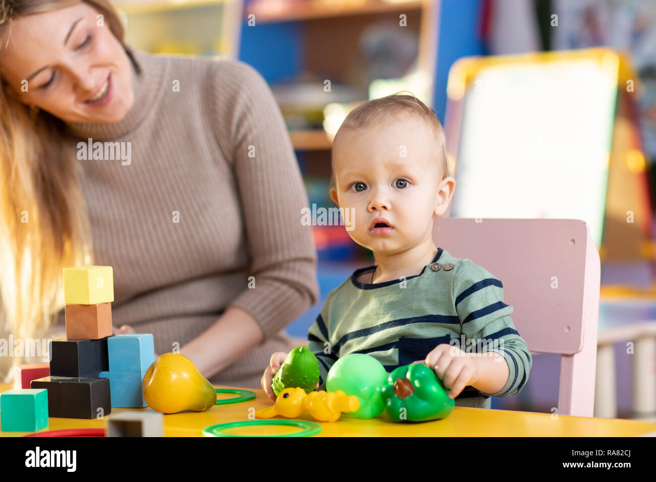 Nursery child playing with teacher in classroom in kindergarten Stock ...