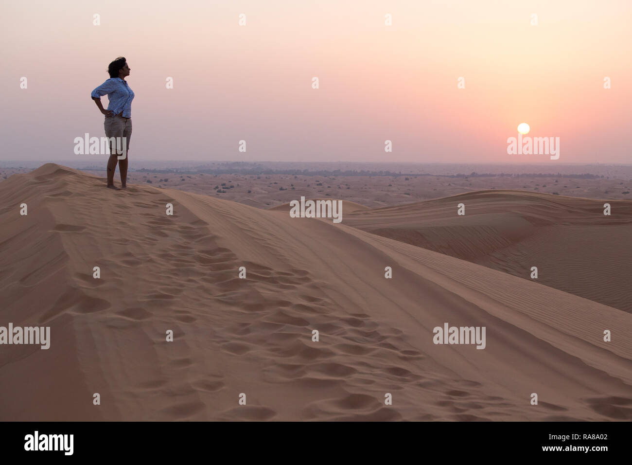 A female Indian tourist poses at sunset in the desert outside Dubai ...