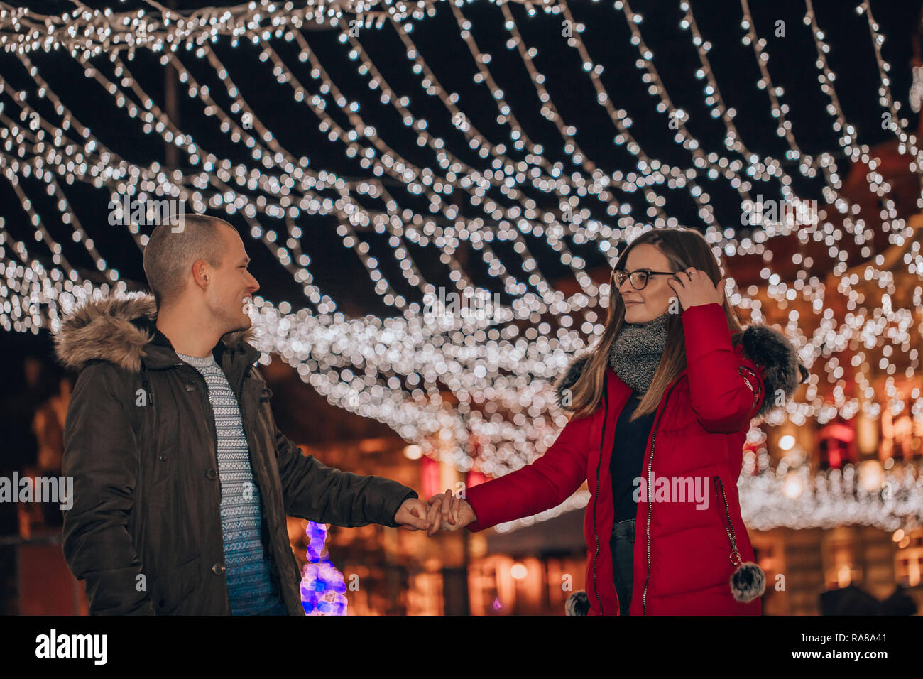 Young couple in winter clothing at the city street holding hands at ...