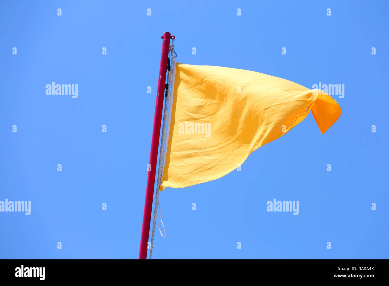 yellow flag waving in the blue sky above the tower of a lifeguard Stock ...