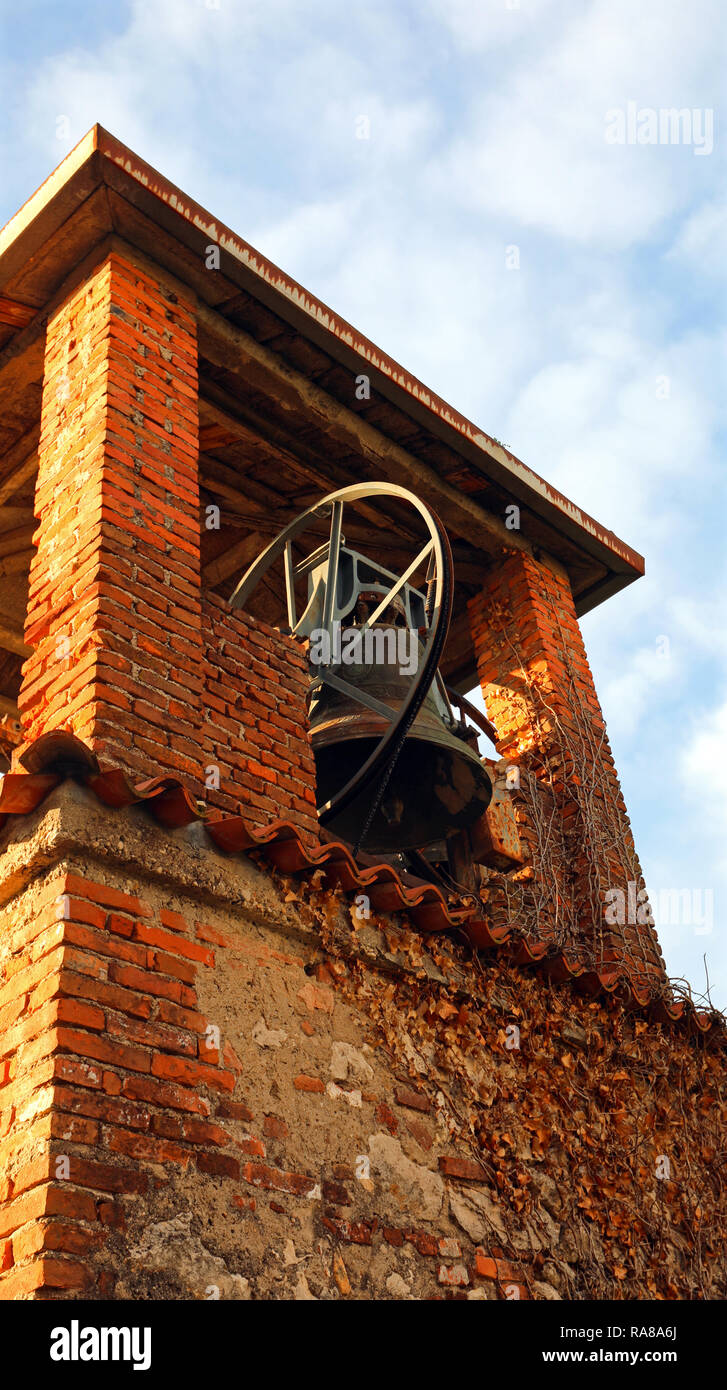 ancient medieval brick bell tower with old bronze bell and blue sky ...