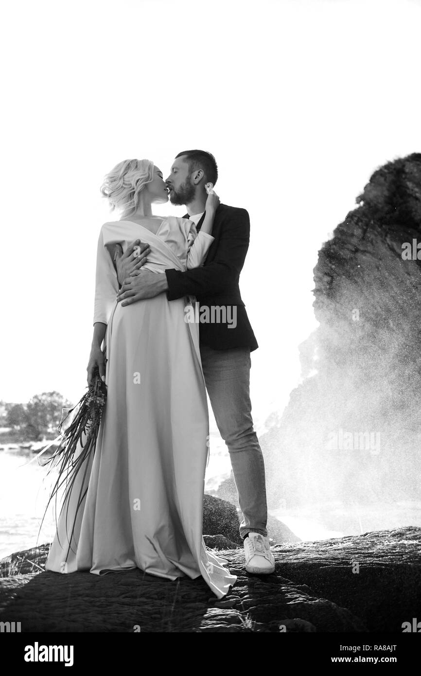 Couple in love stands in the splashes of water against the sunset. A ...