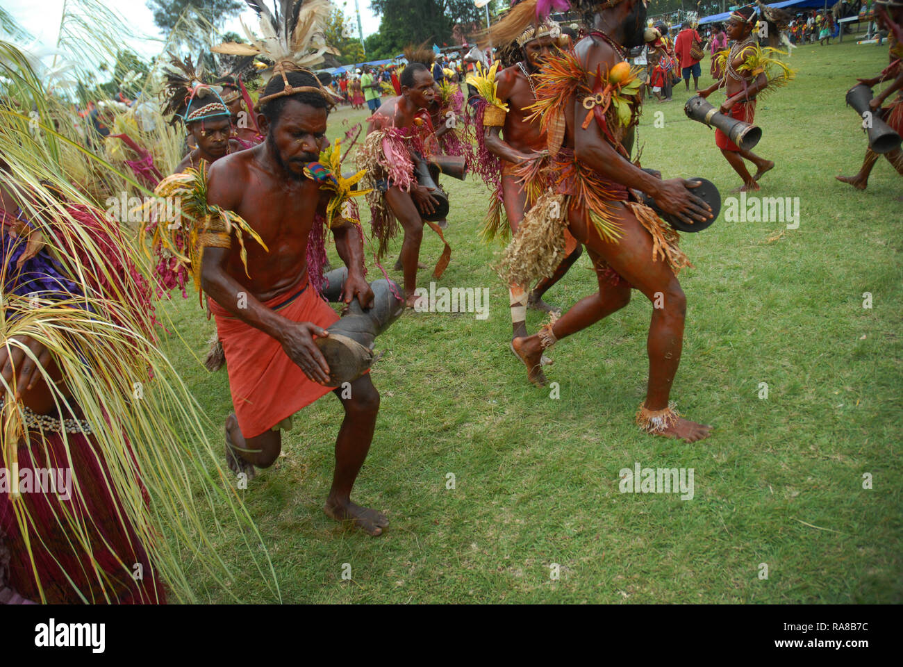 Colourfully dressed and face painted men dancing as part of a Sing Sing ...