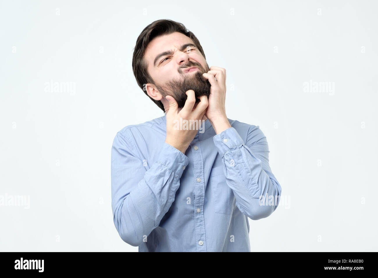 Itching of man skin concept. Young spanish man with black beard ...