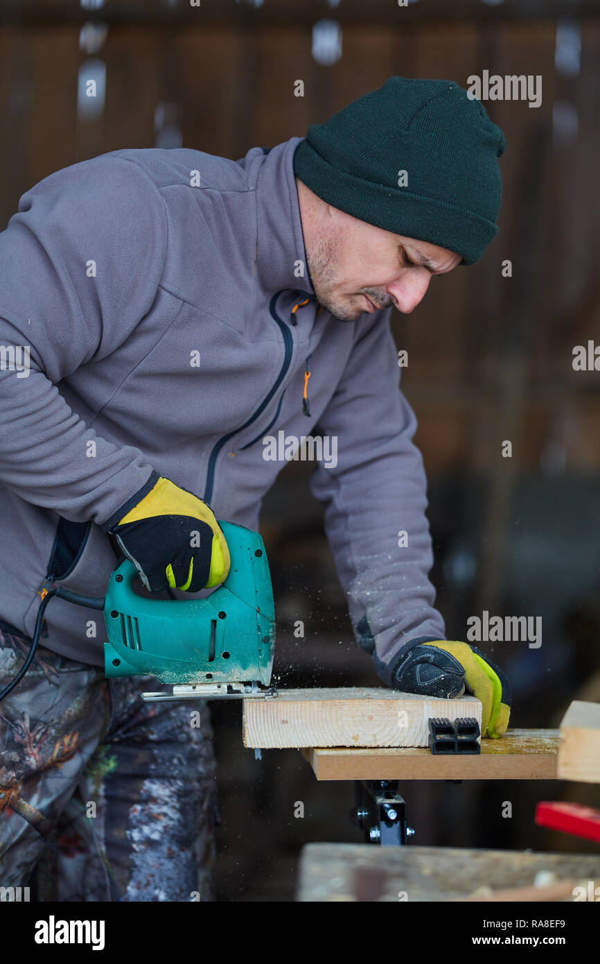Woodworking - man using electric jigsaw to cut pine timber Stock Photo ...