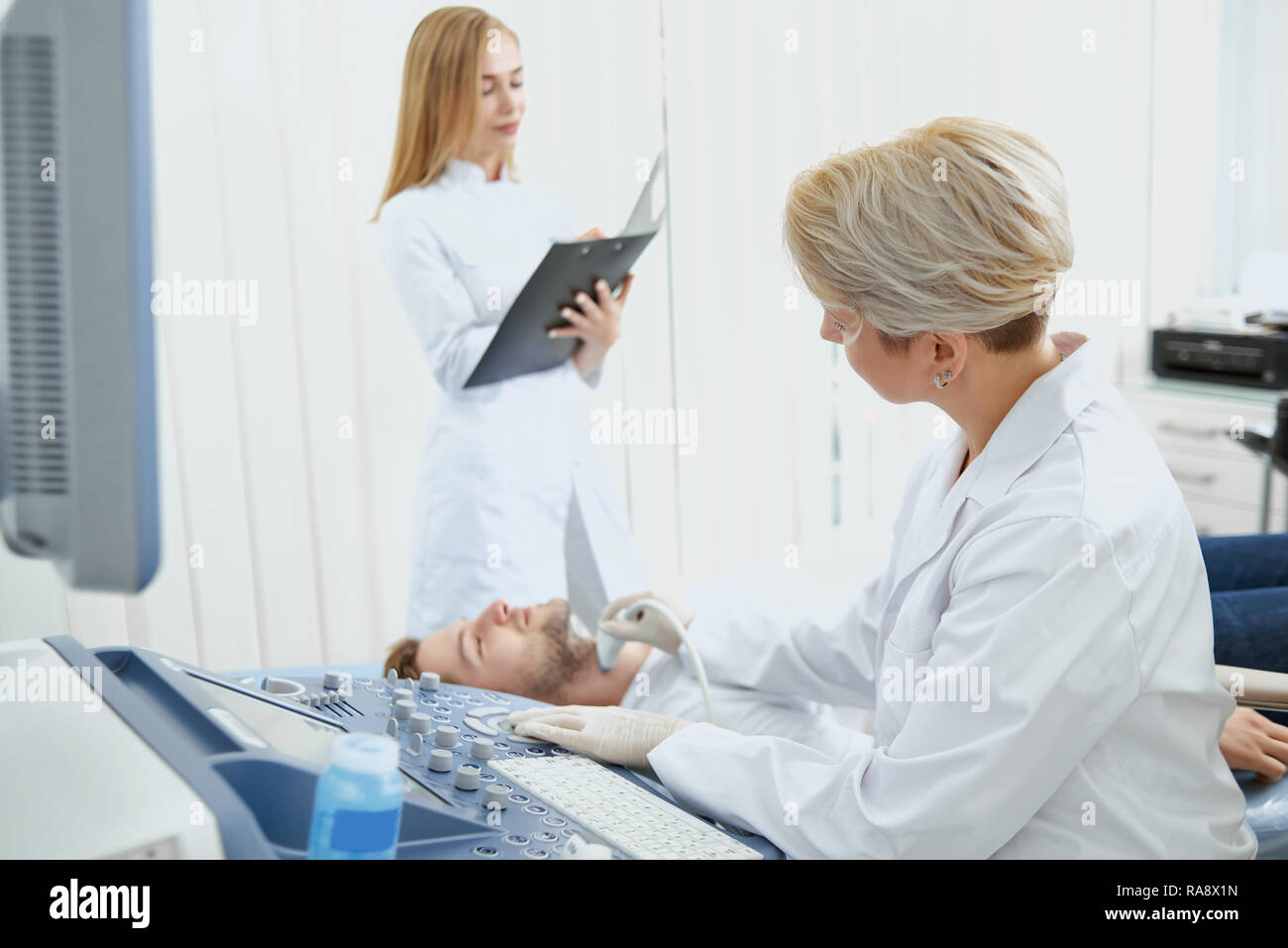 View of people working in hospital. Doctor sitting and observing client ...