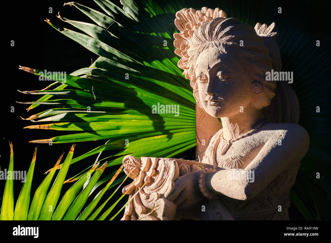 Traditional Balinese sandstone statue of woman, welcome offering in her ...
