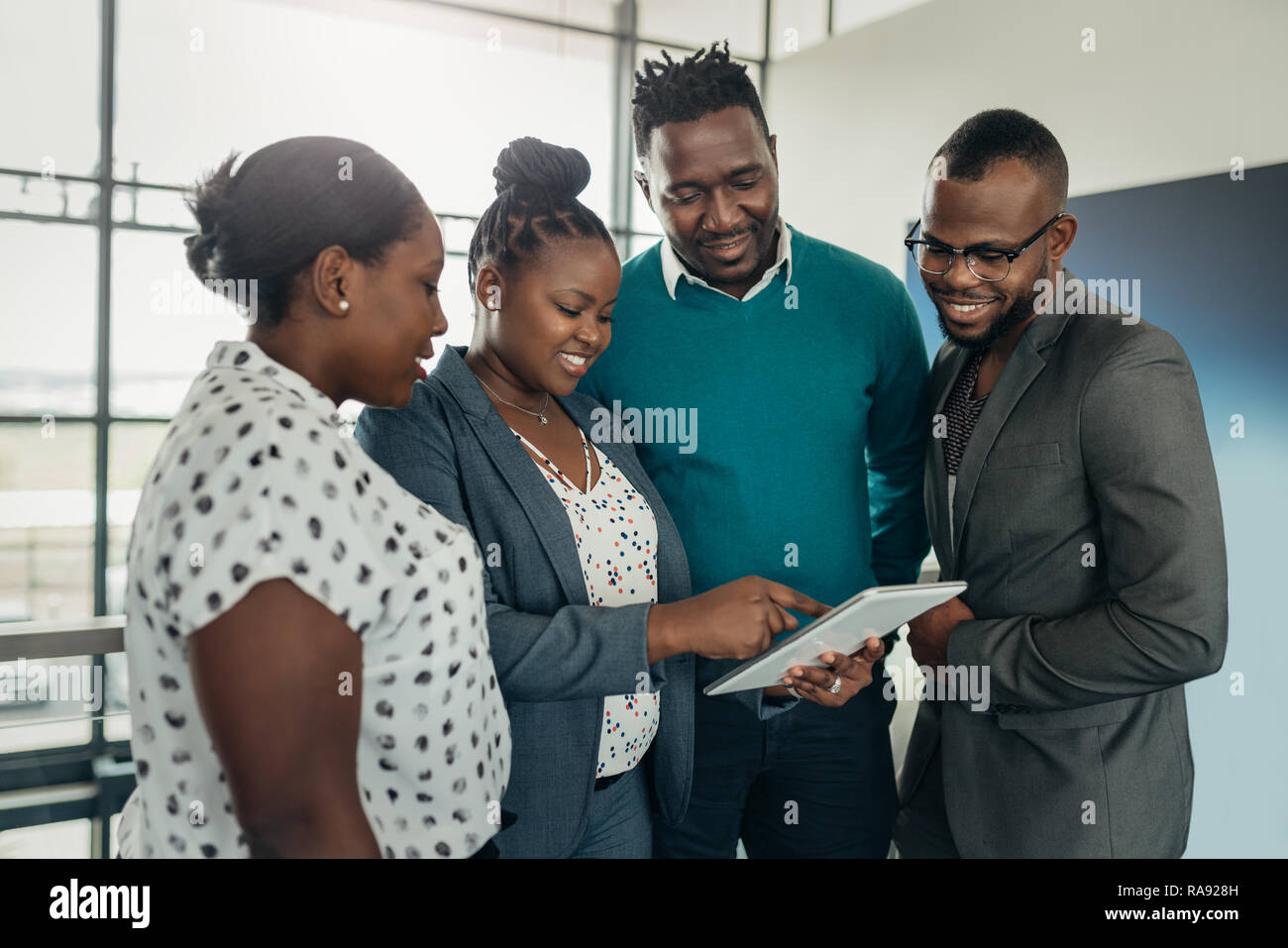 Team of african business people standing and discussing, using a tablet ...