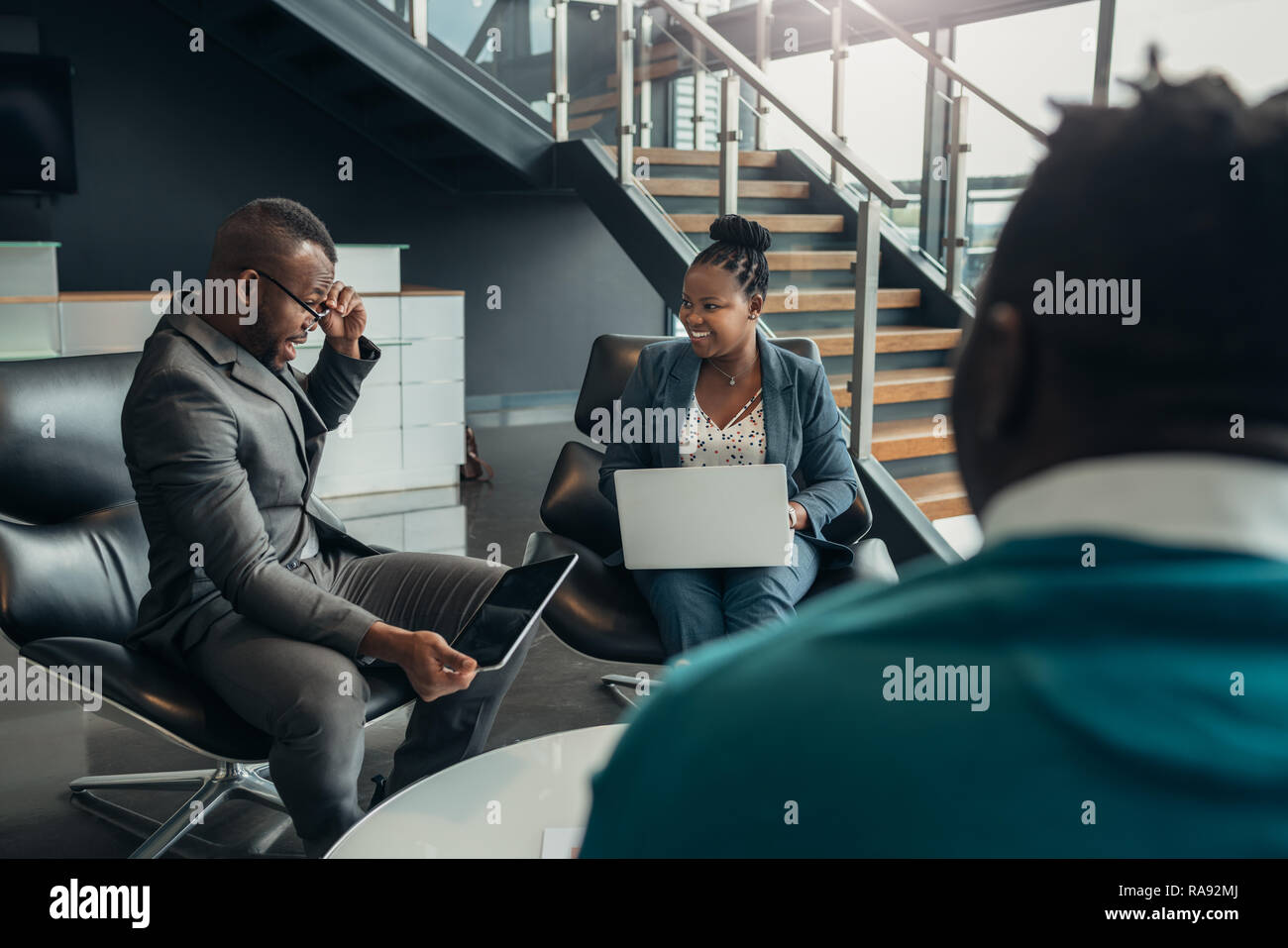 Two friendly African buiness people in a meeting chatting casually ...