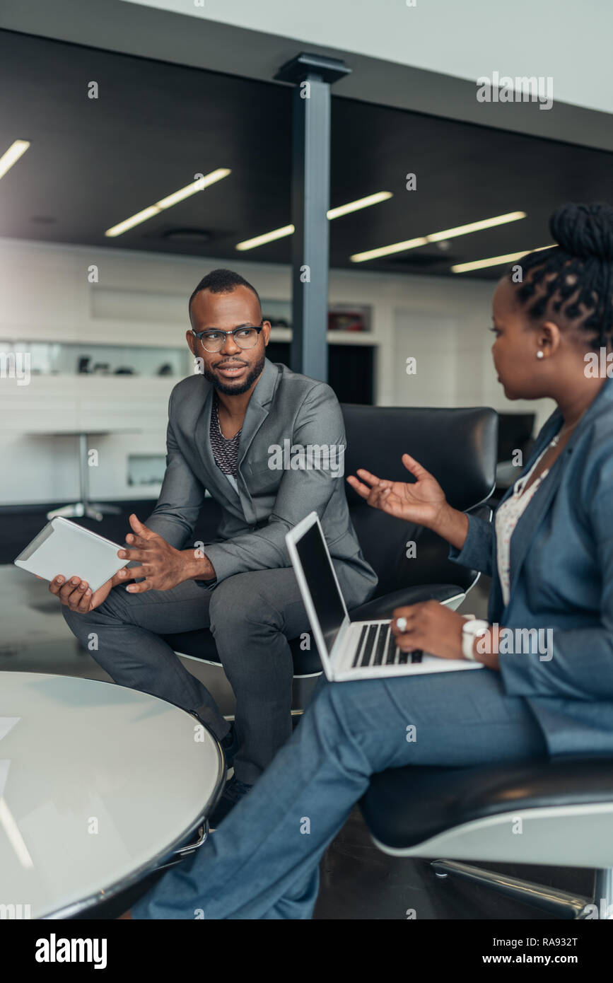 Two african business people talking seriously with hand gestures during ...