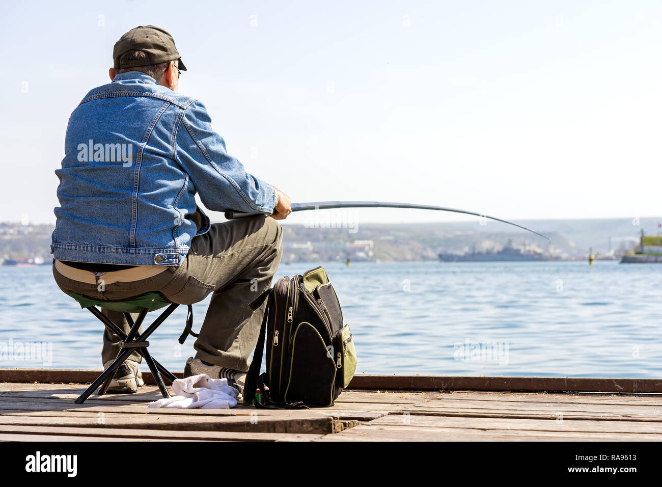 fisherman catches fish from the dock in the port Stock Photo - Alamy