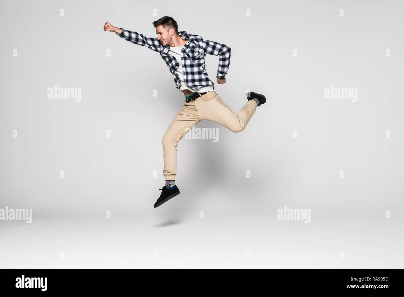 Full length portrait of a young man jumping with hands outstretched ...