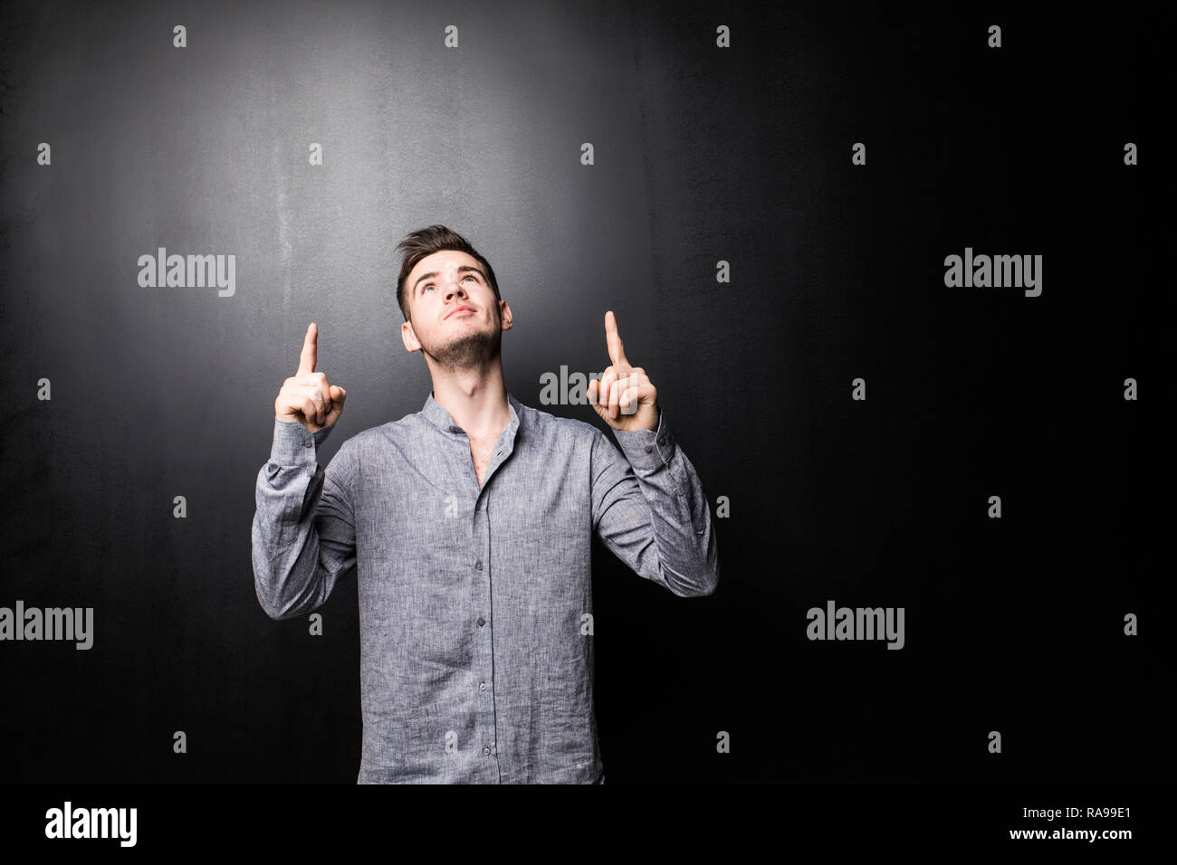 Portrait of man in checkered shirt pointing fingers up over white ...
