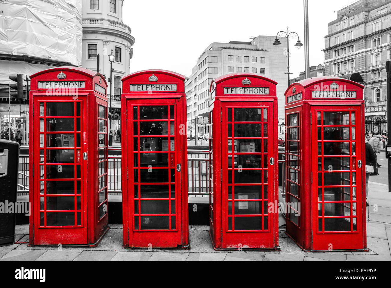 Four traditional British red telephone boxes are standing on the street ...