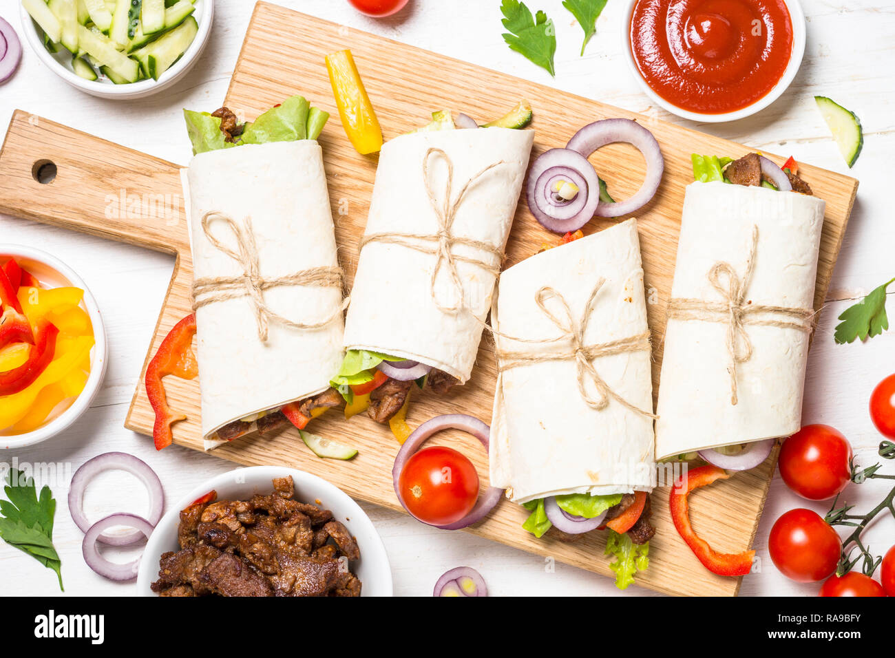 Burritos tortilla wraps with beef and vegetables on white wooden ...