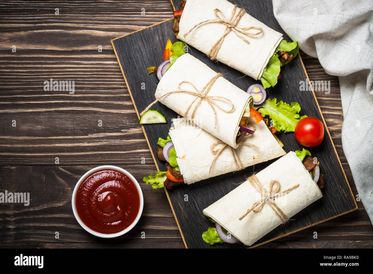 Burritos tortilla wraps with beef and vegetables on wooden table ...