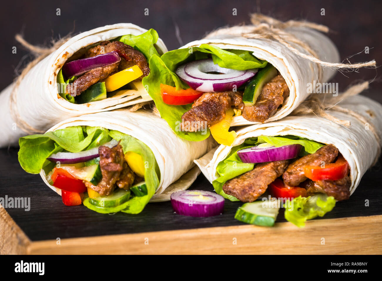 Burritos tortilla wraps with beef and vegetables on wooden table ...