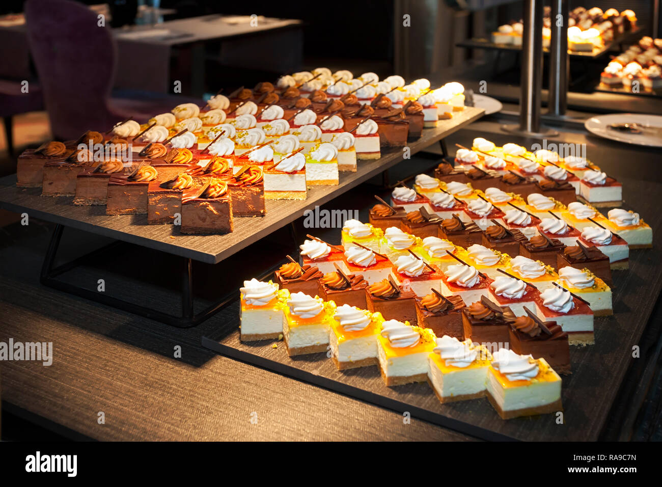 Small chocolate and vanilla layered cakes in rows on candy buffet ...