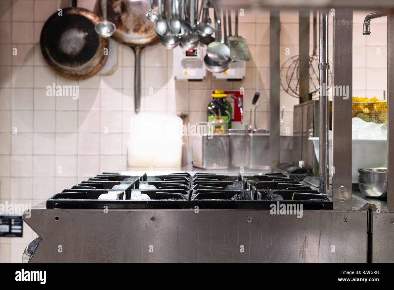 Side view of kitchen gas stove top with steel kitchen utensil in ...