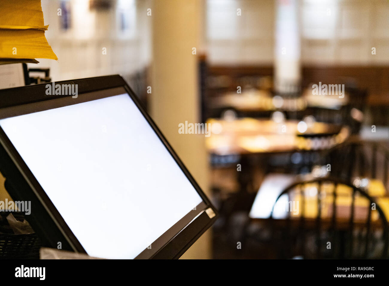 Close up of empty computer display monitor, restaurant room with table ...