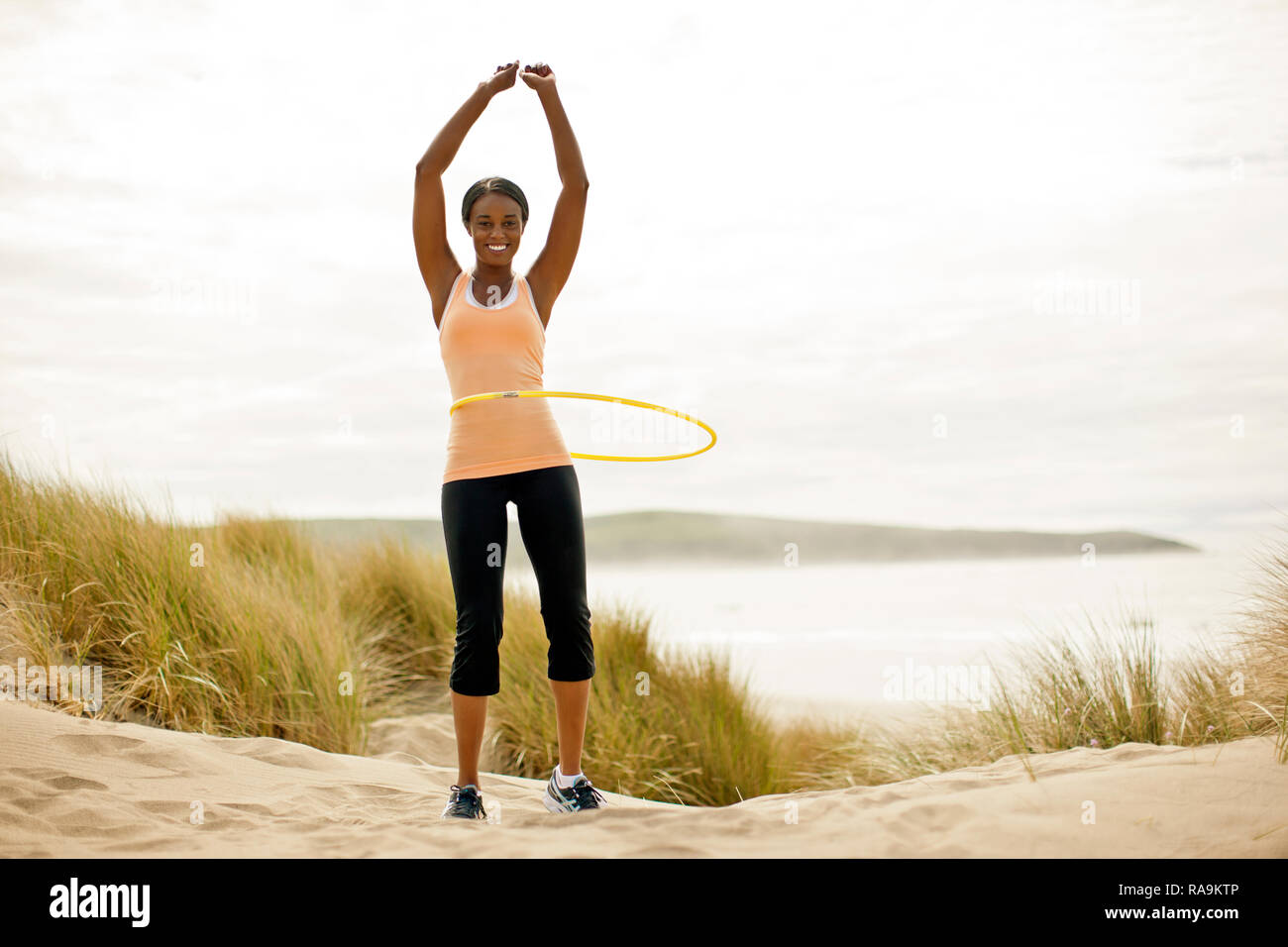 Portrait of a happy young woman hula hooping in her living room Stock ...