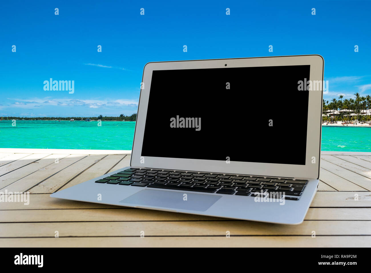 Laptop computer on wooden table. Front ocean view. Tropical island ...