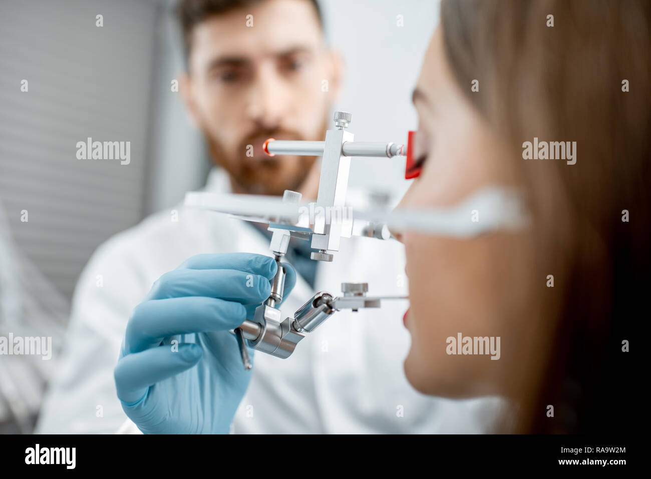 Dentist putting jaw measurement system to a young woman patient in the ...