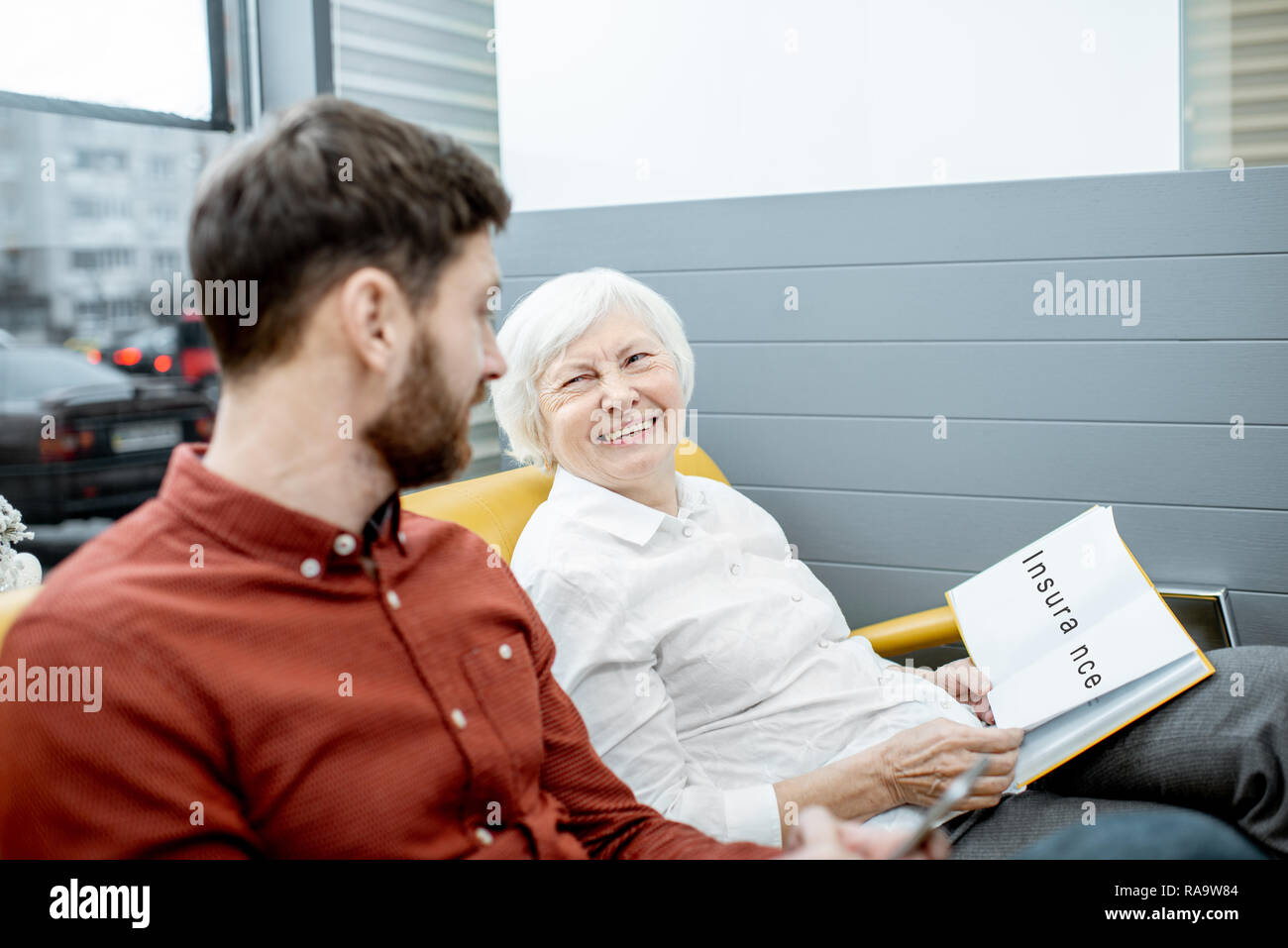 Man with smiling senior woman holding insurance at the hospital ...
