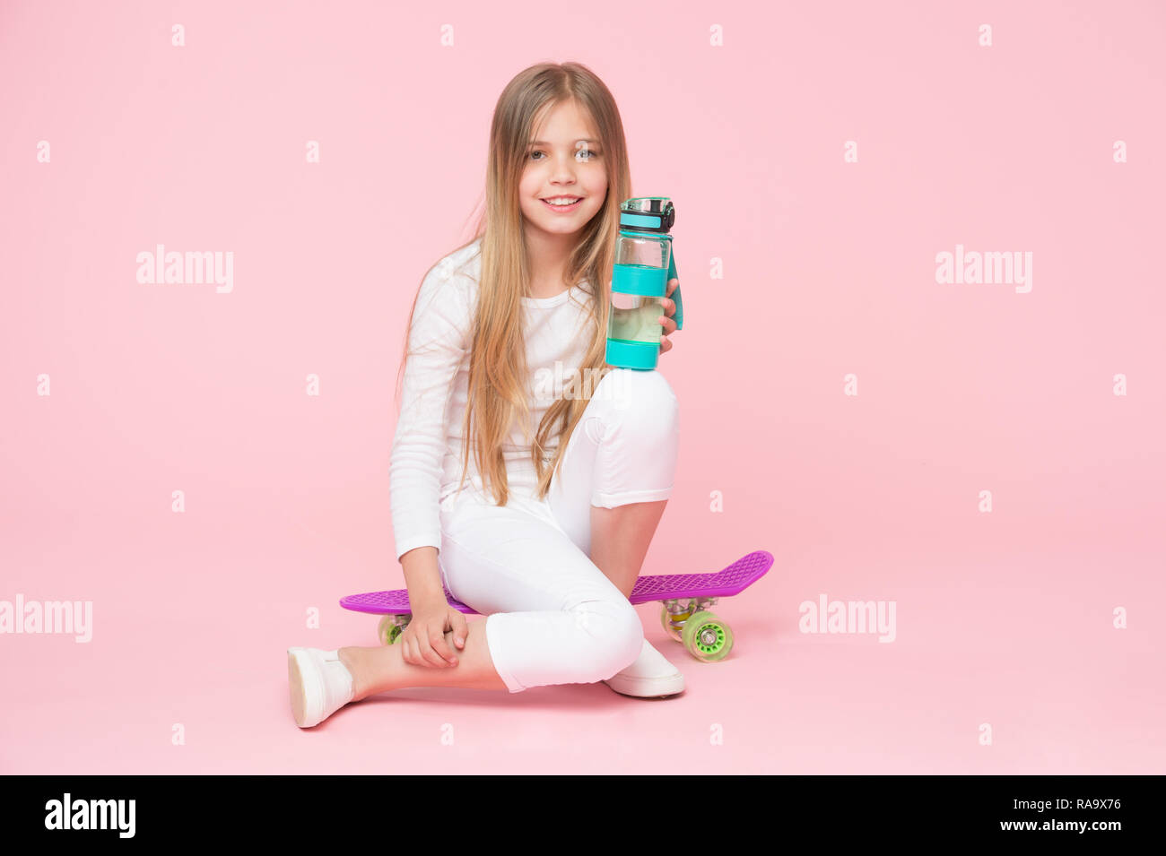 Girl happy face holds with water bottle while sit penny board pink ...