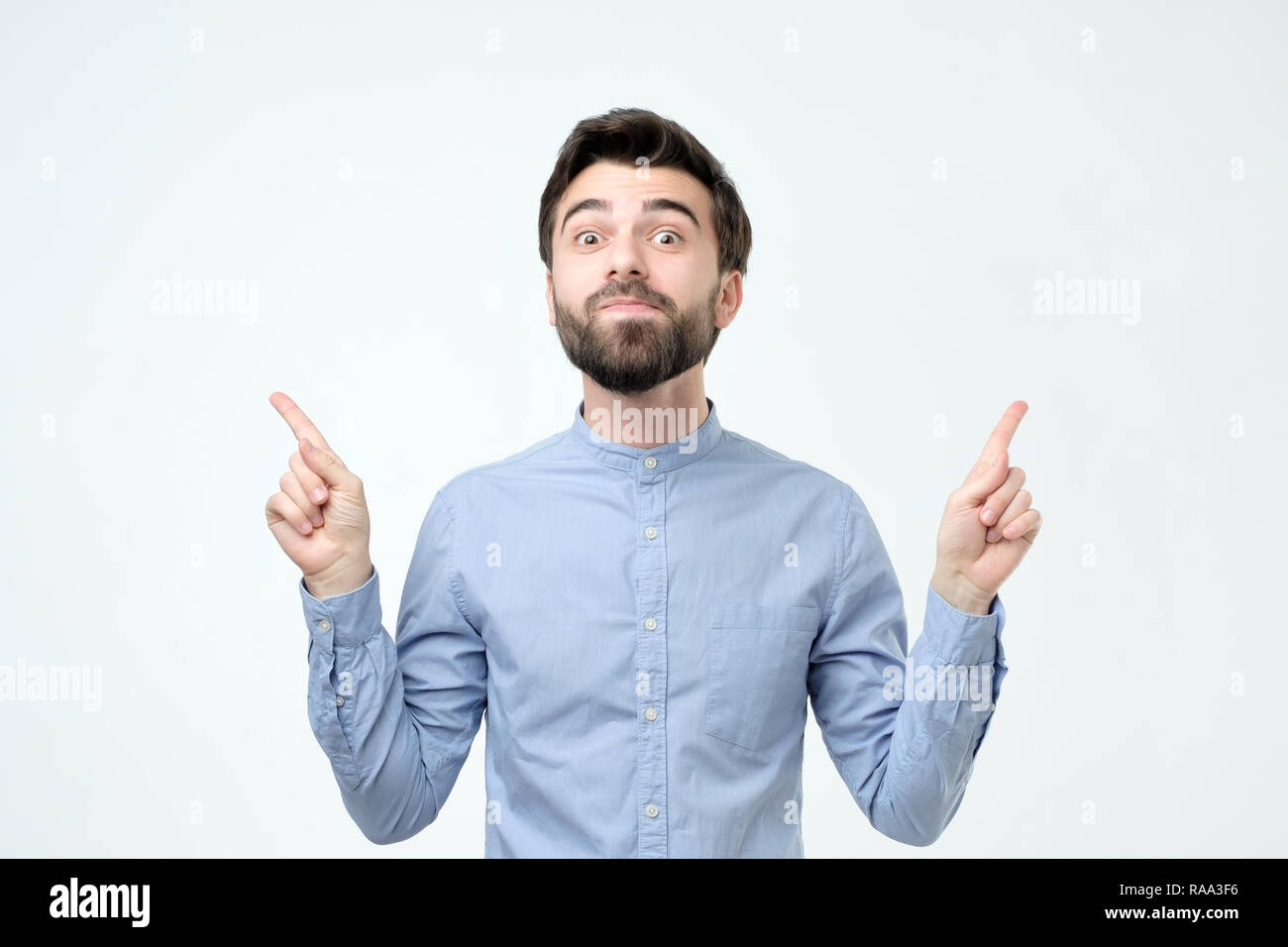 Man in blue shirt pointing up with his finger isolated on gray ...