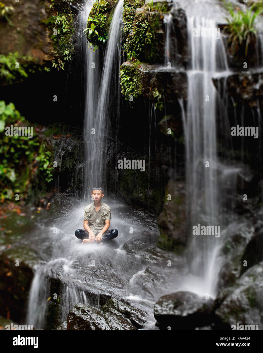 Young Vietnamese boy sitting under the water at Thac Gio Waterfall ...