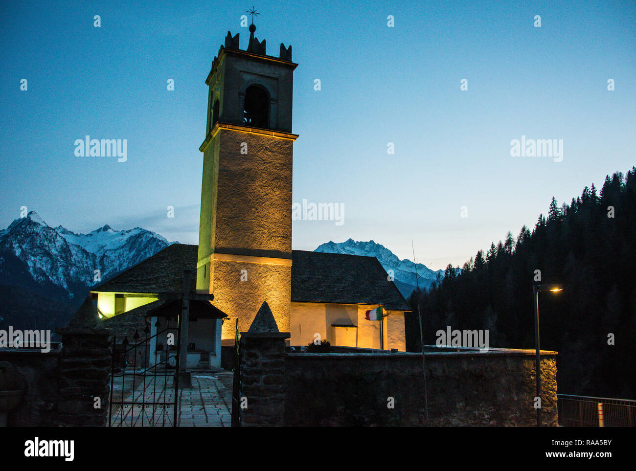 Night photo of mountain church with bell tower and cross on it. Italian ...