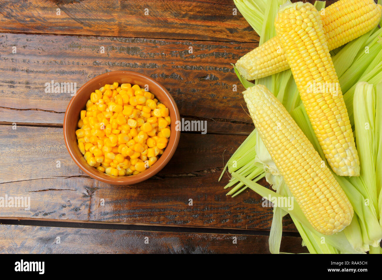 Raw corn kernels, inside ceramic bowl, next to corn on the cob on ...