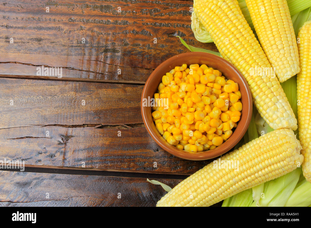 Raw corn kernels, inside ceramic bowl, next to corn on the cob on ...