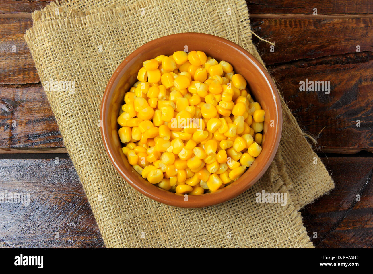 Raw corn kernels inside ceramic bowl on rustic wooden table. space for ...