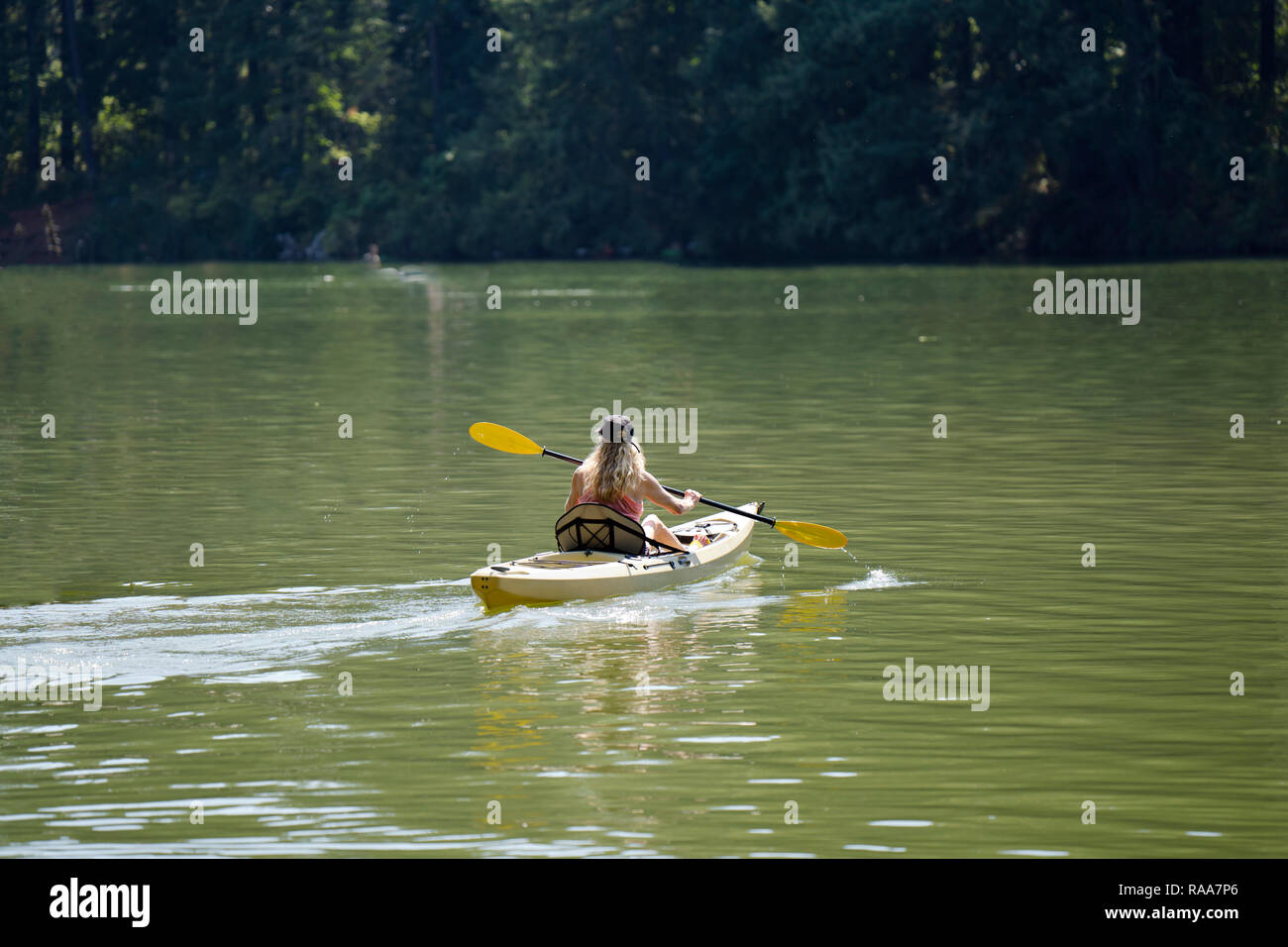 An enthusiast woman with long hair in bathing suit are kayaking on the ...