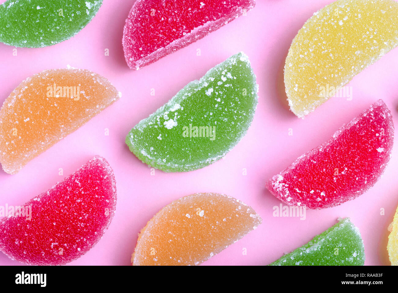 colored jelly slices with sugar crystals, on pink background Stock ...