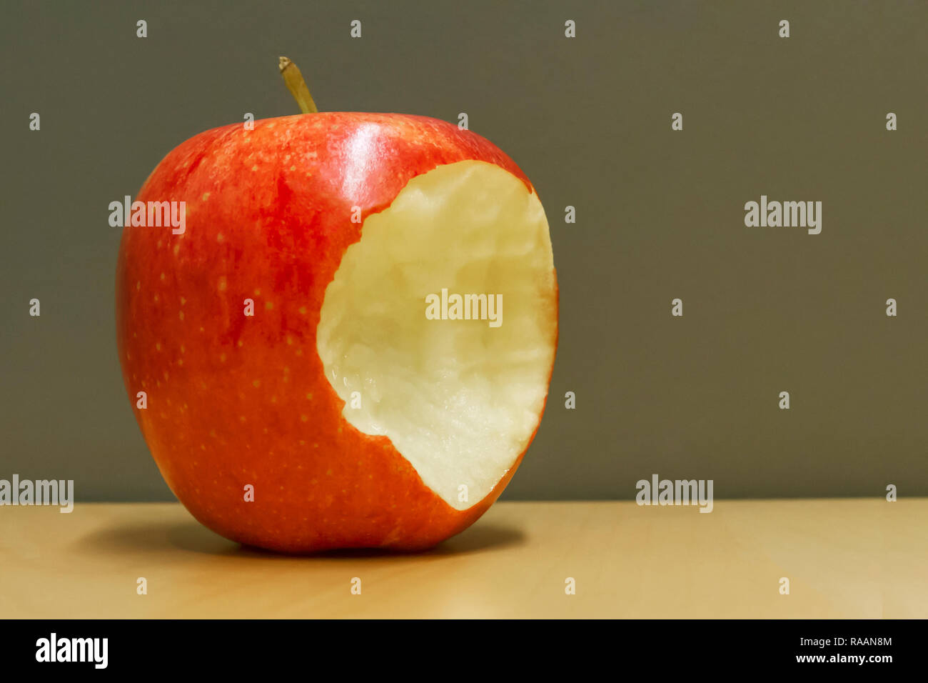 red bitten apple on green background Stock Photo - Alamy