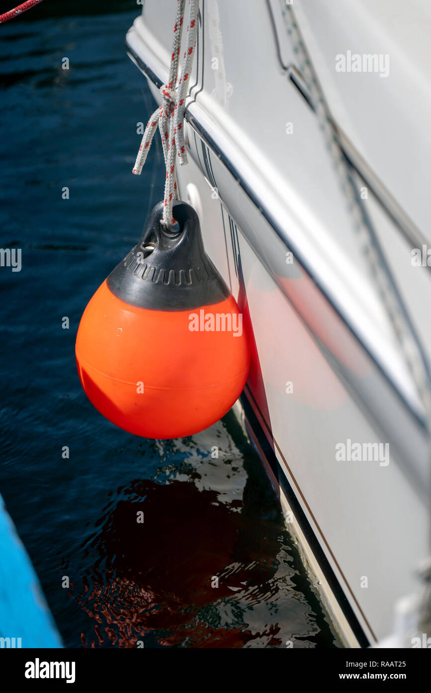 Plastic bright round float attached overboard of the motor boat to ...