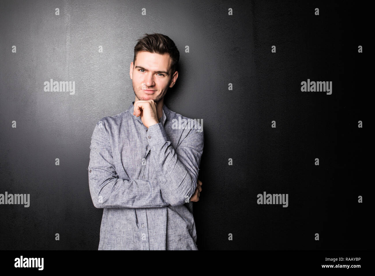 Handsome young man standing and looking up isolated on the gray ...