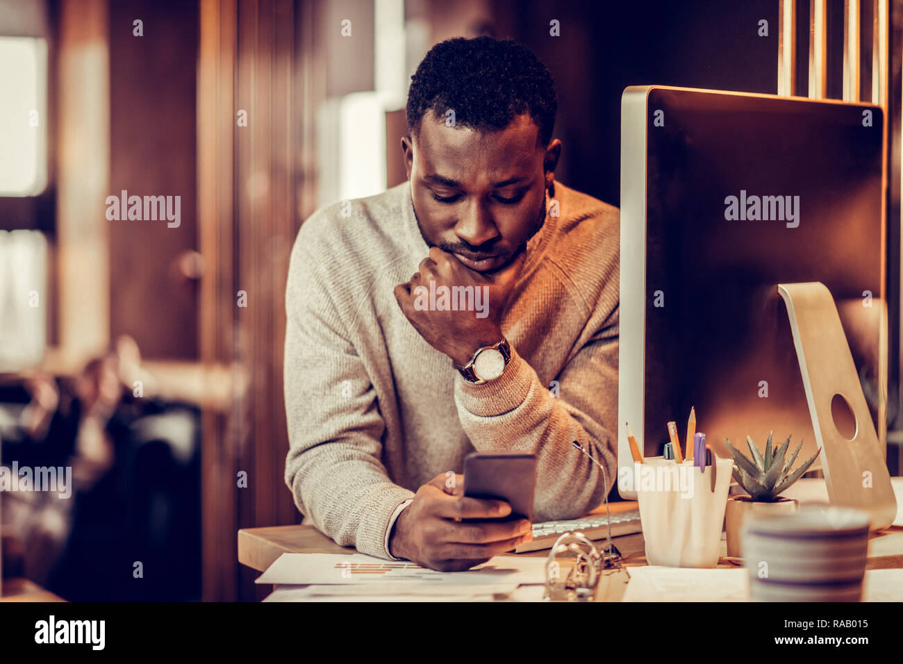 Serious dark-skinned man staring at his smartphone Stock Photo - Alamy