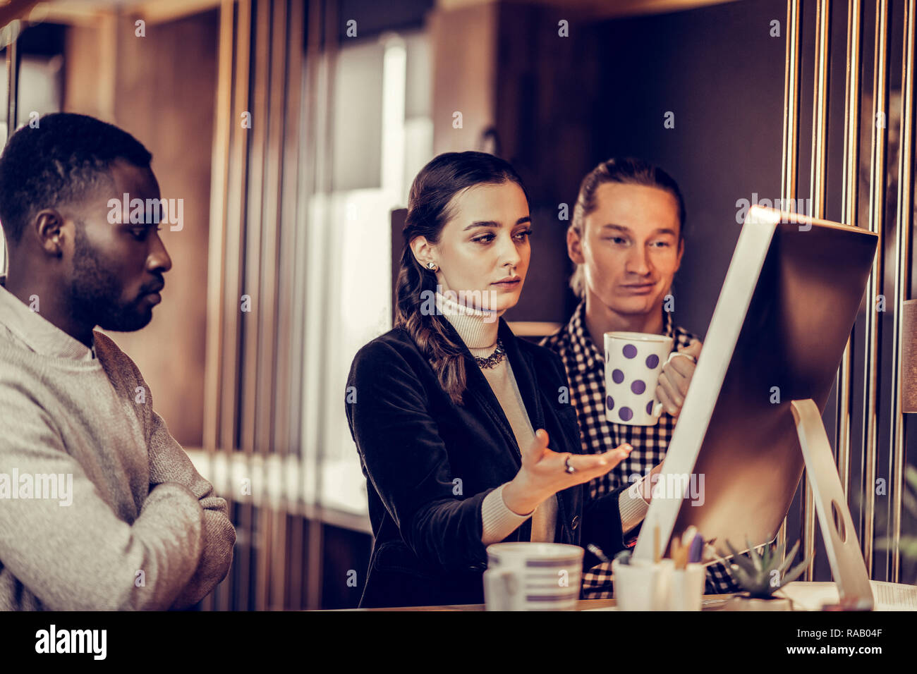 Serious brunette girl pointing at screen of computer Stock Photo - Alamy