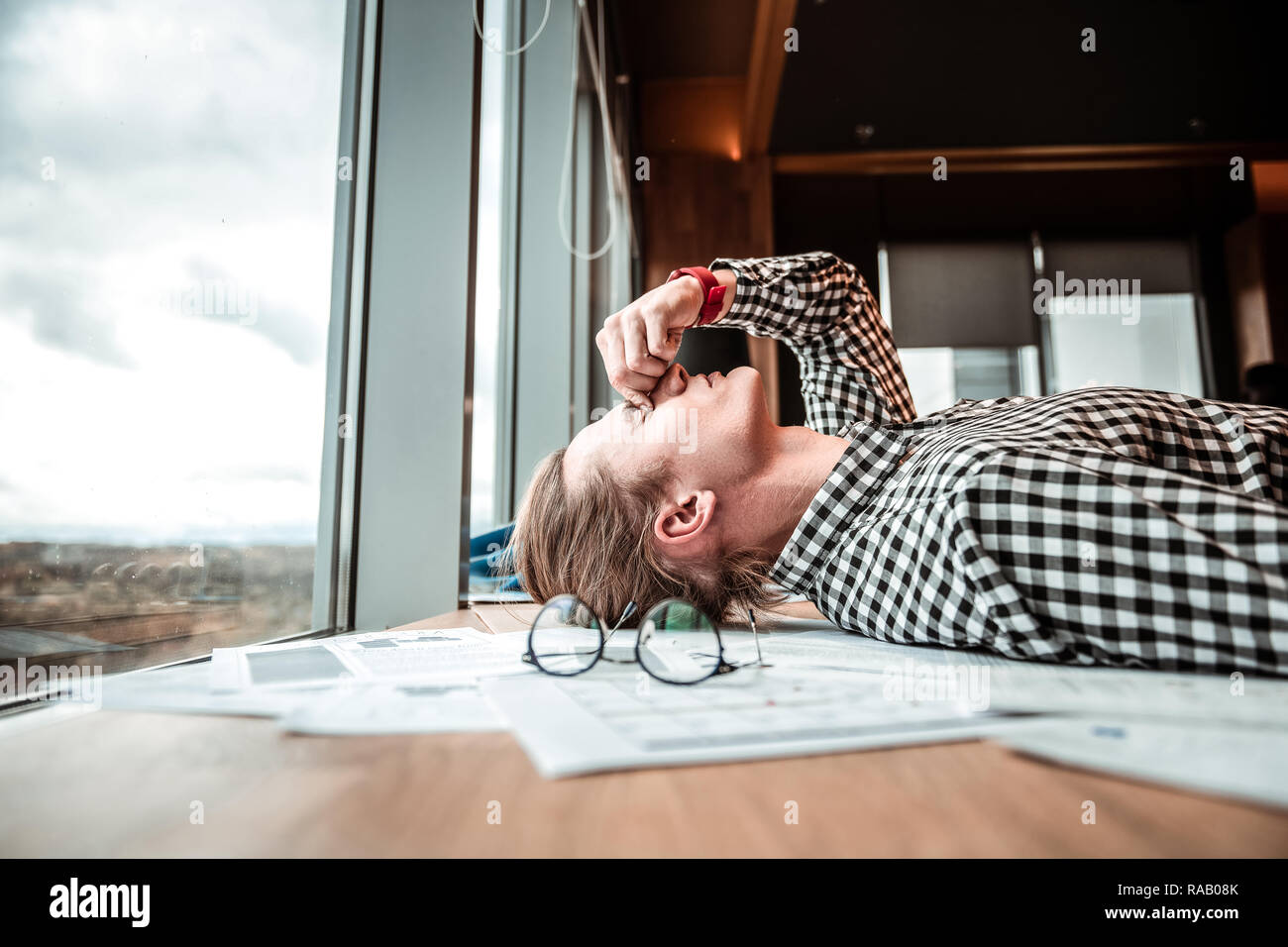 Young man lying on his workplace on pause Stock Photo - Alamy