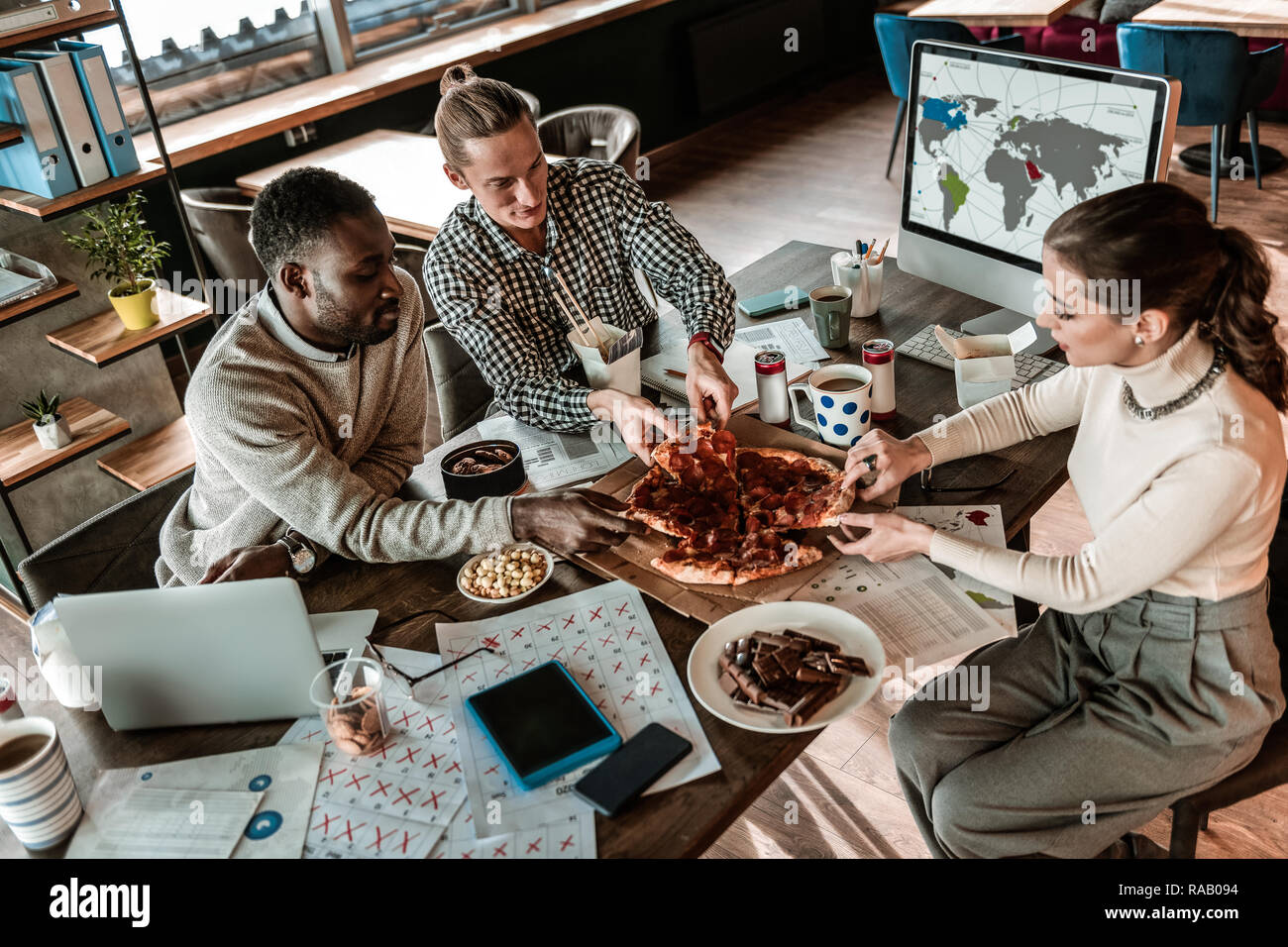 Relaxed colleagues going to eat pizza at workplace Stock Photo - Alamy