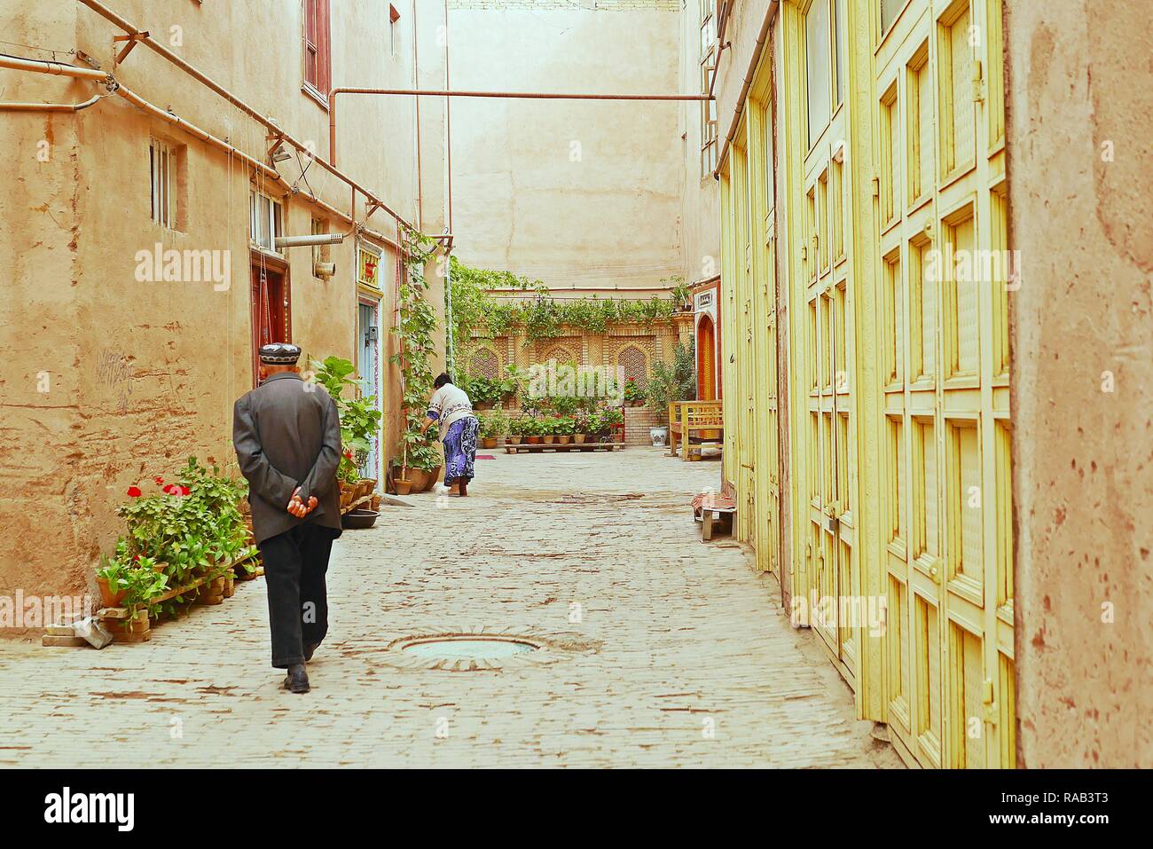 Street view of an old Muslim Uyghur man walking down the street in ...