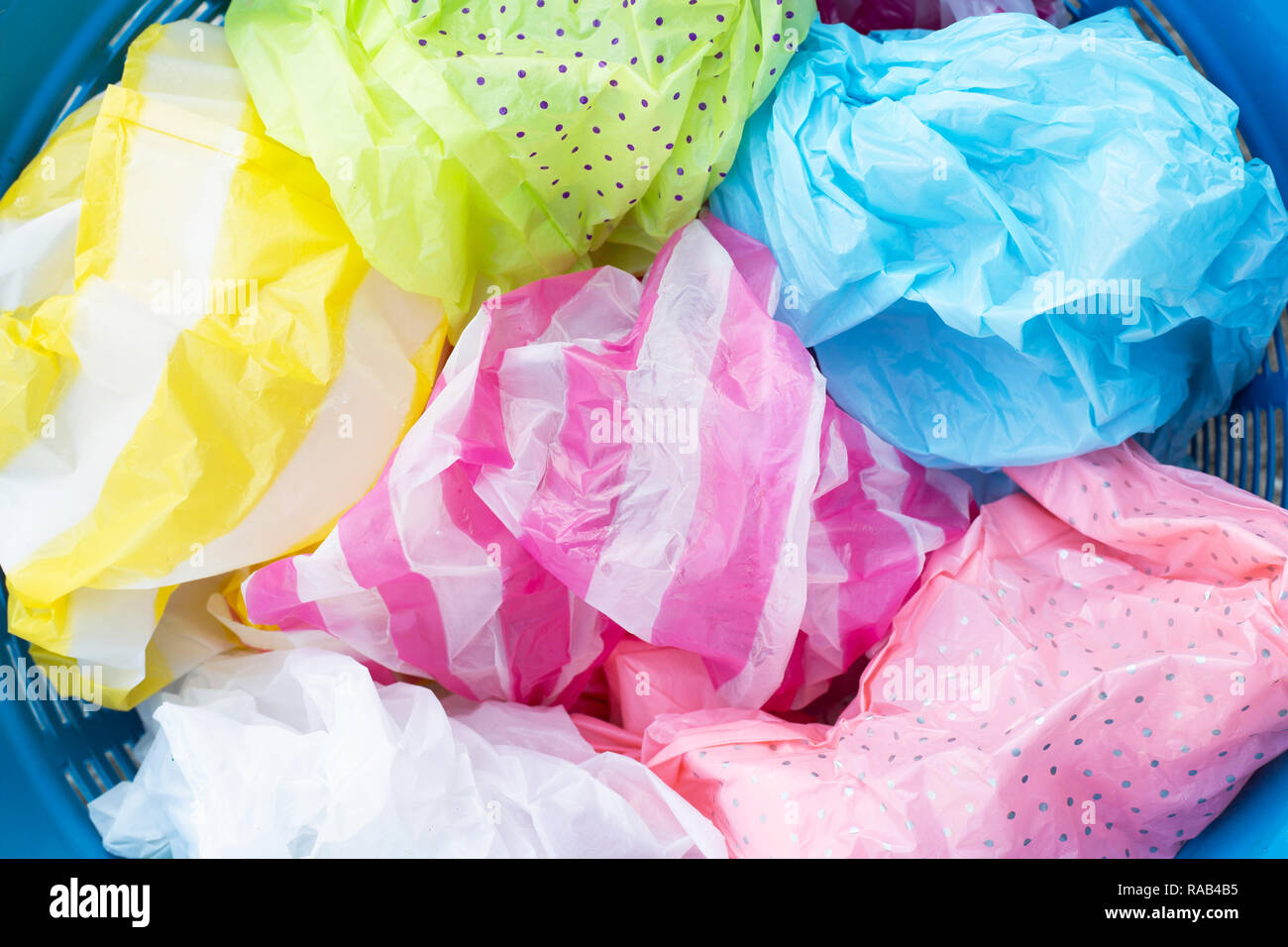 Colorful plastic bags in blue waste basket Stock Photo - Alamy
